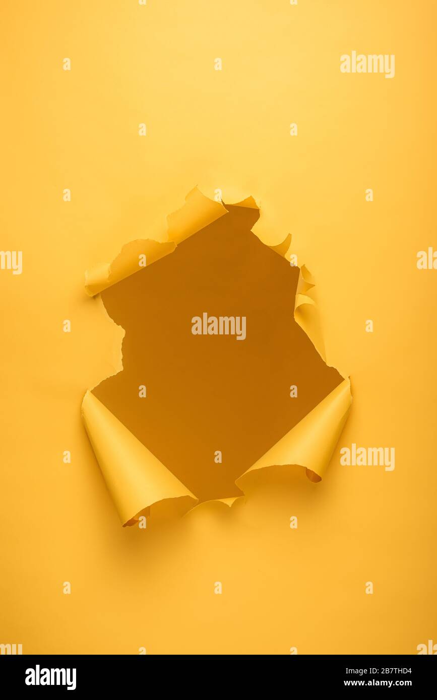 torn hole in yellow paper texture with copy space Stock Photo - Alamy