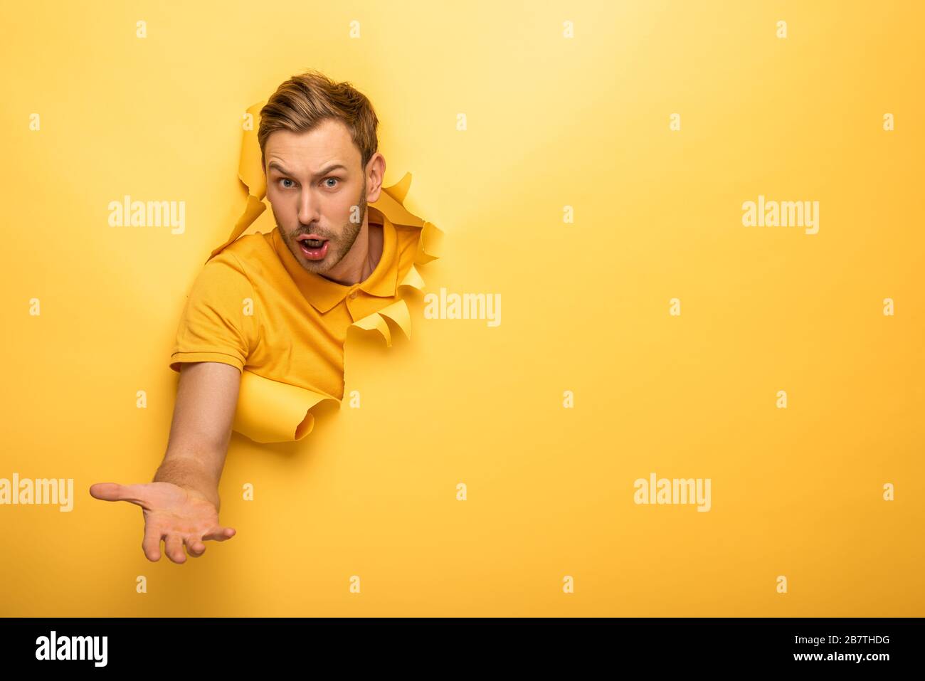 confused handsome man in yellow outfit in yellow paper hole Stock Photo ...