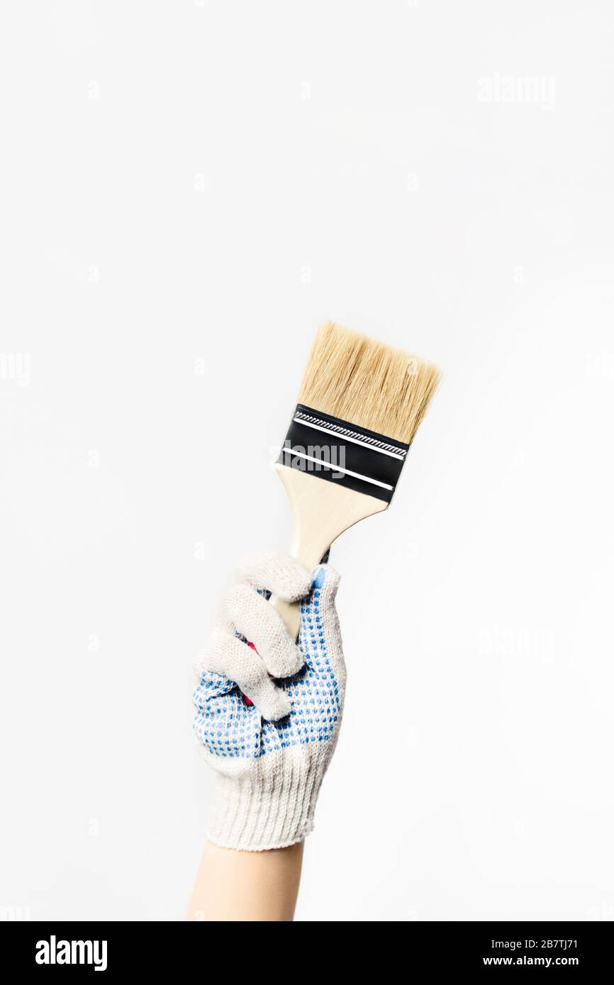A woman 's hand in a construction glove holding a construction brush ...