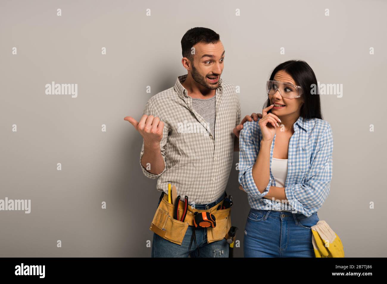 frightened manual workers talking at pointing on grey Stock Photo - Alamy