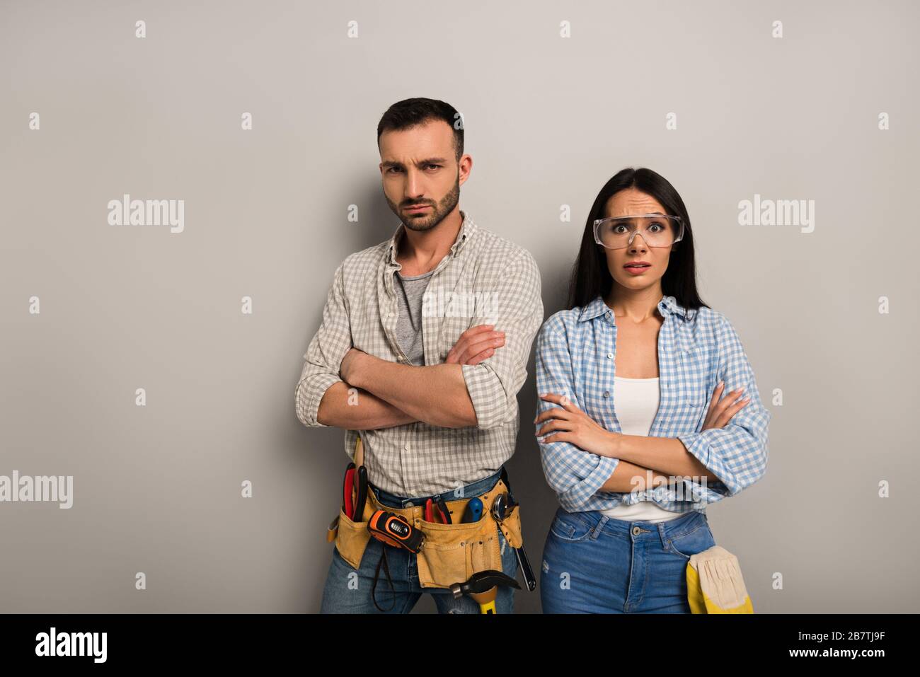 frustrated manual workers standing with crossed arms on grey Stock ...