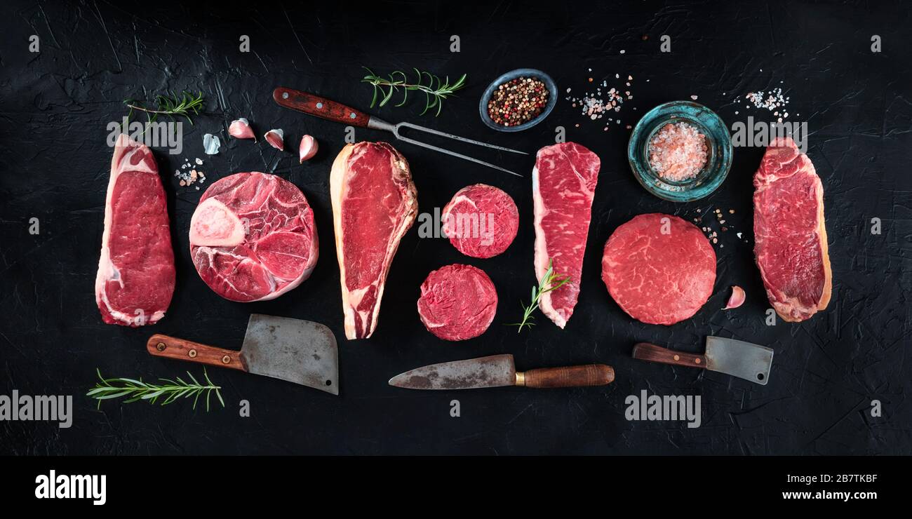 Various cuts of meat, shot from the top on a black background with ...