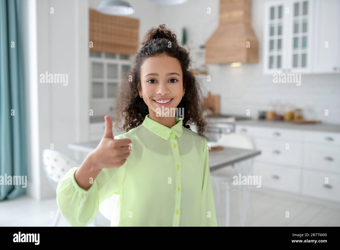 Dark-haired girl with curly hair smiling showing thumb up Stock Photo ...