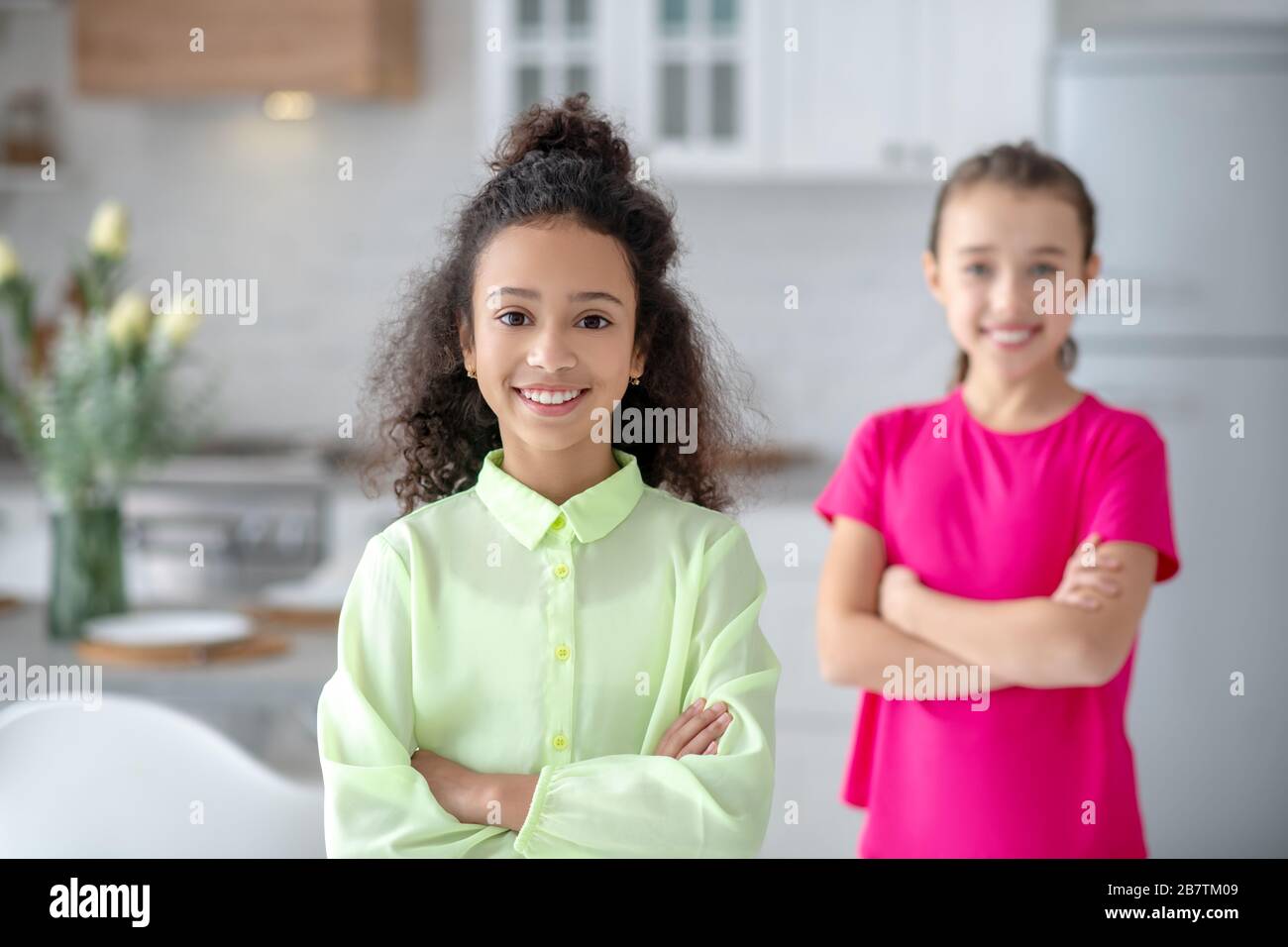 Two girls standing in the kitchen and smiling Stock Photo - Alamy