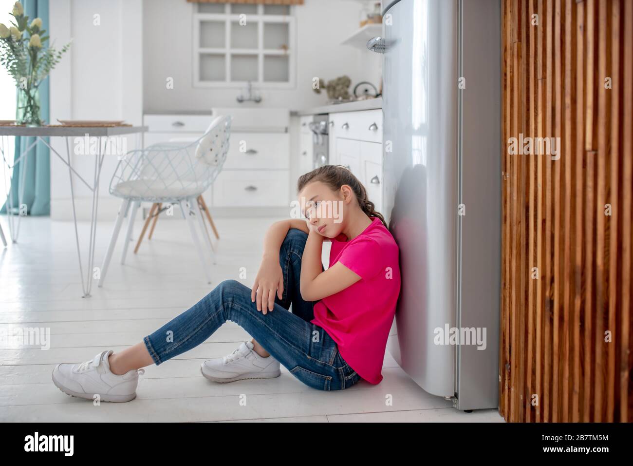 Girl in bright tshirt sitting on the floor feeling sad Stock Photo - Alamy