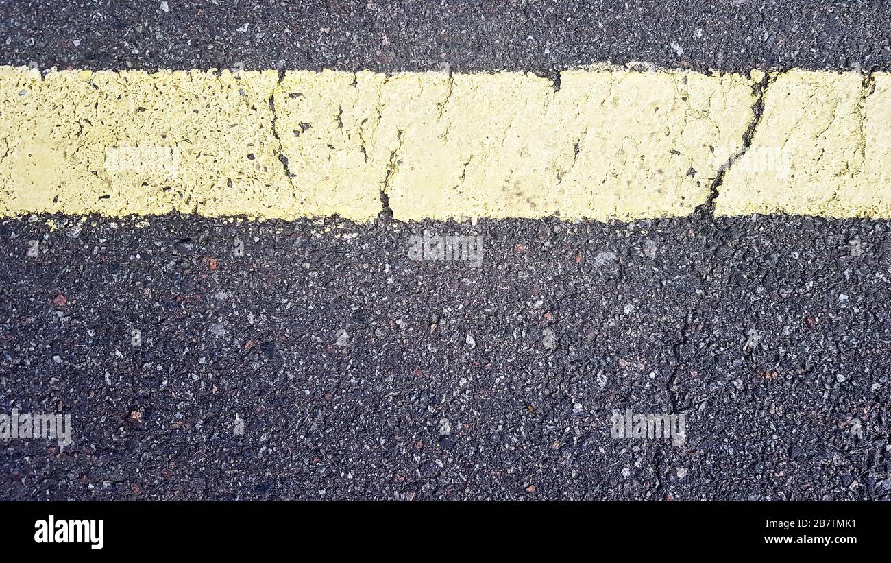 yellow horizontal strip on asphalt. Detail of a yellow stripe worn over ...