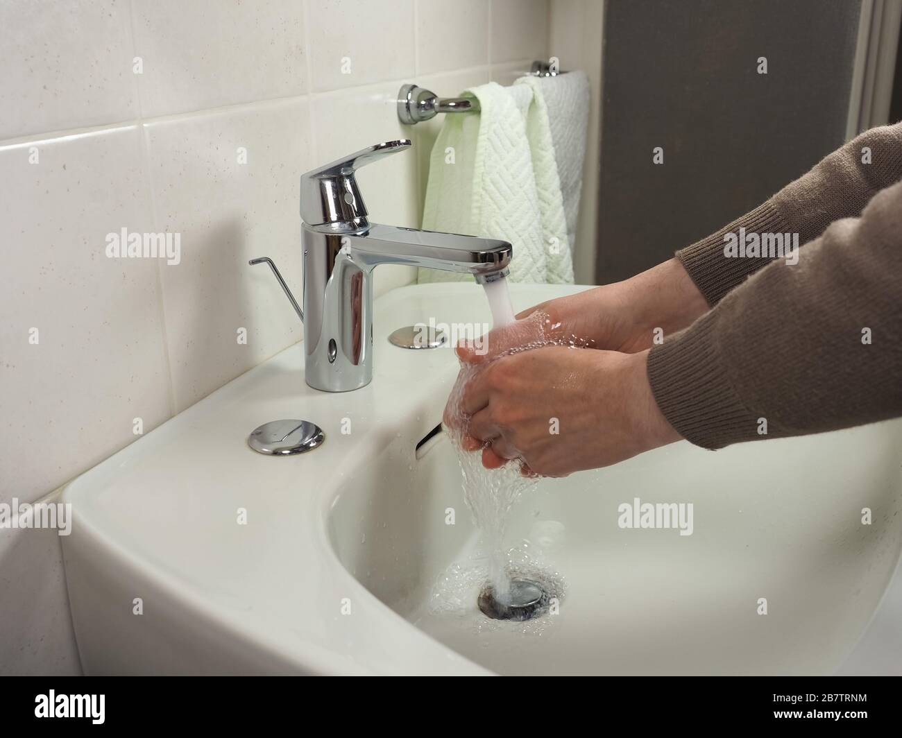 Unrecognisable man carefully washing hands at home for health safety ...