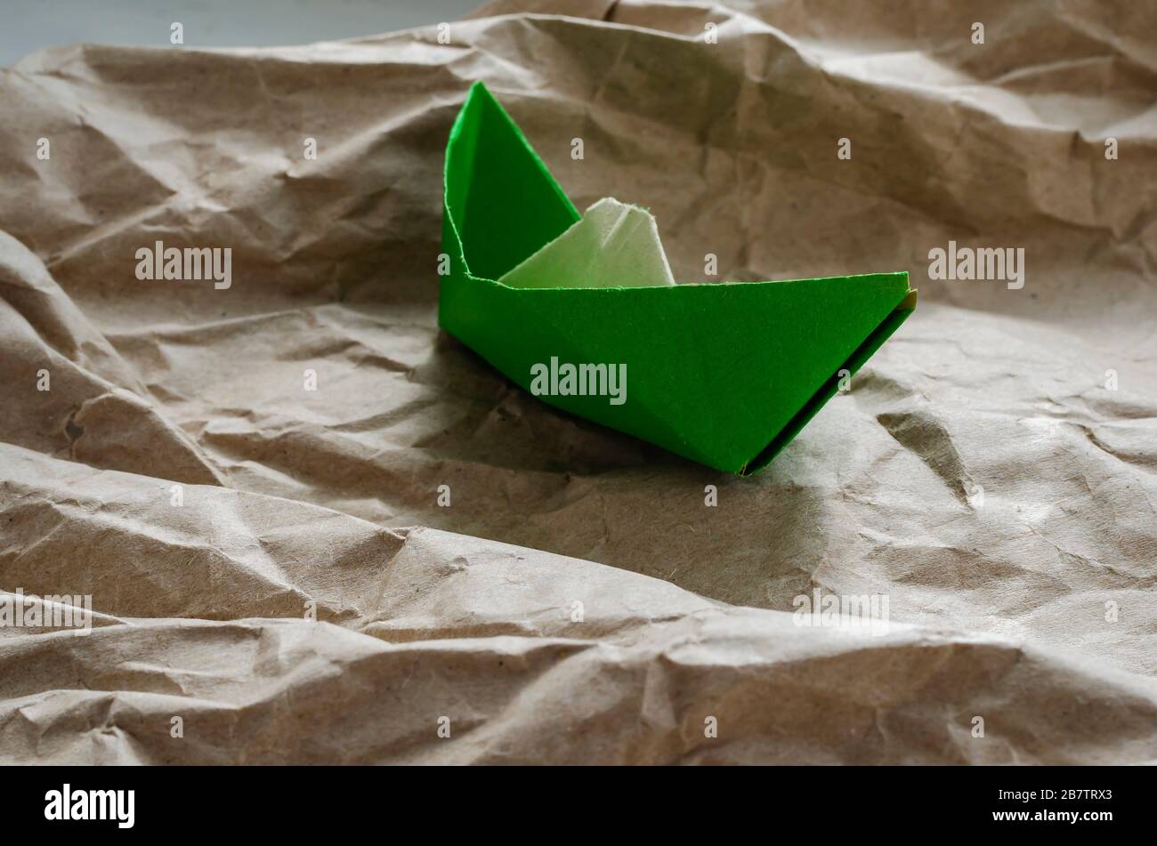 Old paper boat on paper waves. Origami from jammed and torn green paper ...