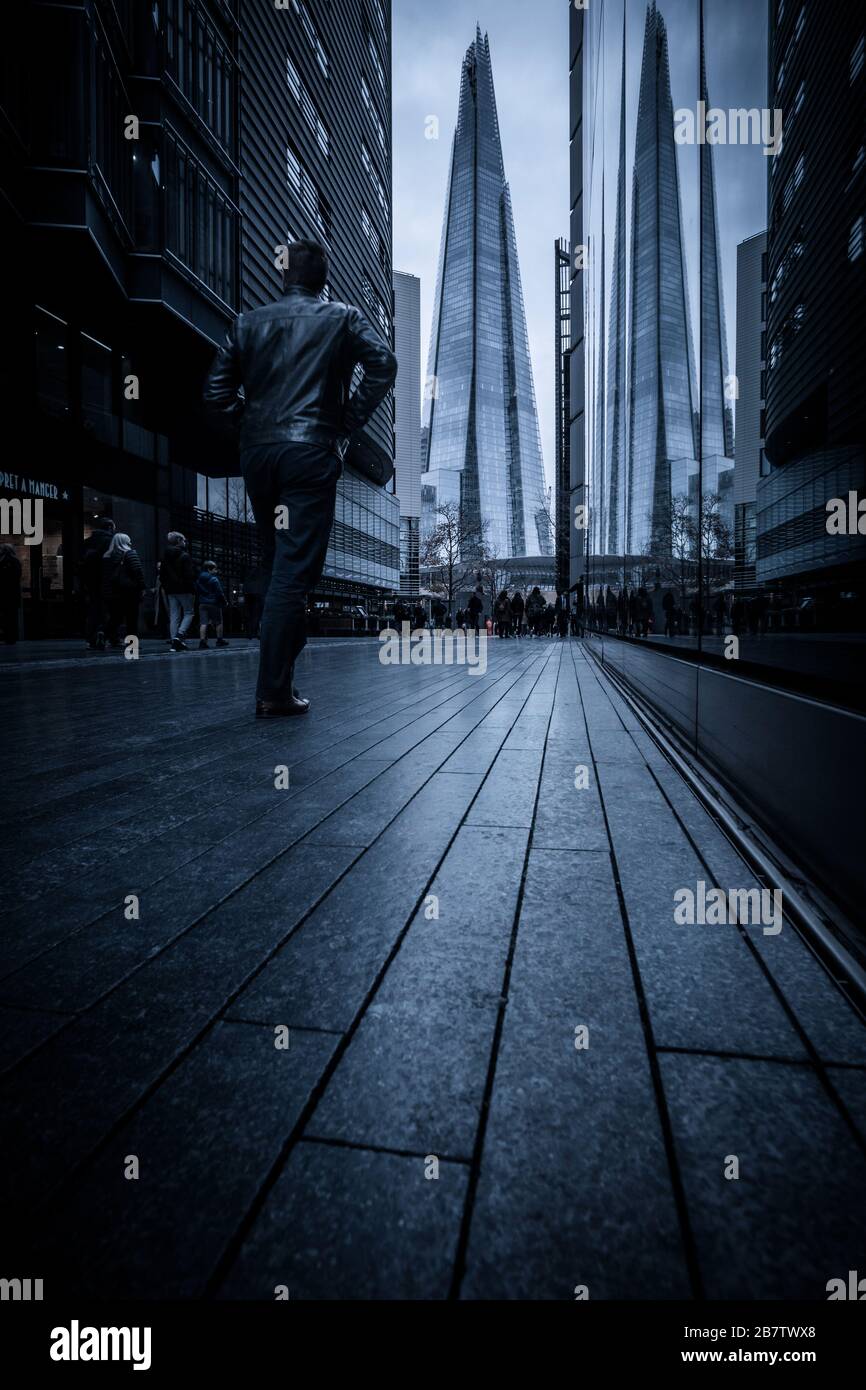 A moody image of a man walking along a street in London with The Shard ...