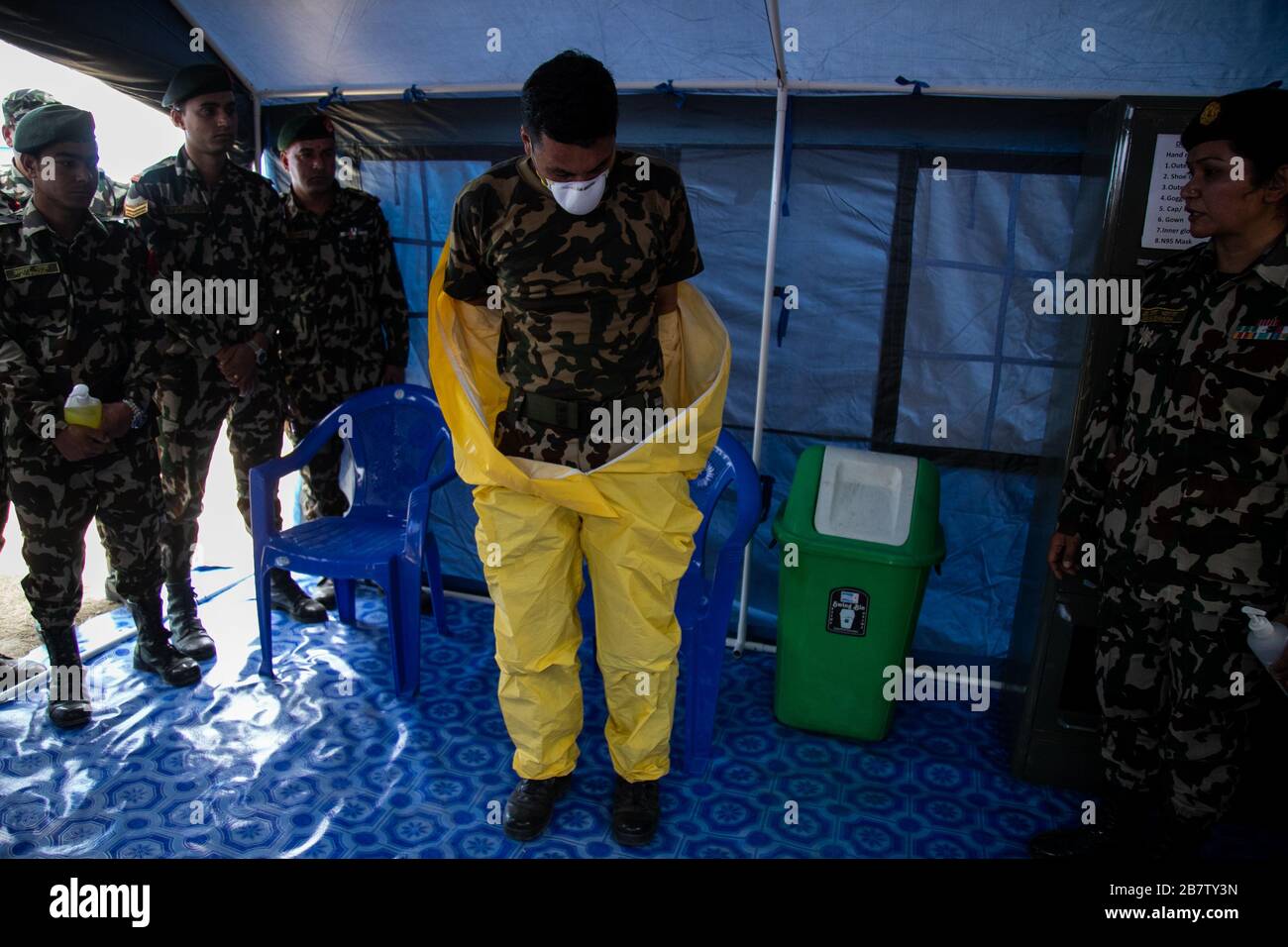 A Nepalese army Officer demonstrates how to remove a protective suit ...