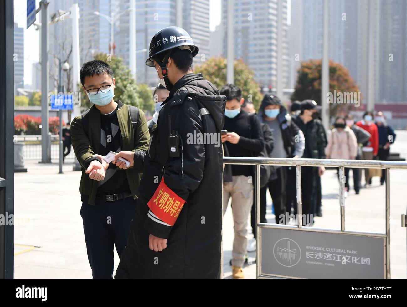 Changsha. 18th Mar, 2020. A staff member checks visitors' body ...