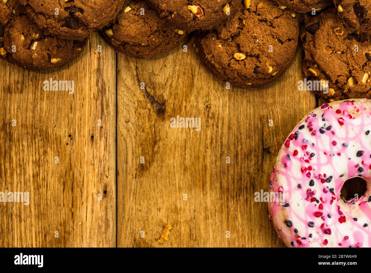 Frame made of chocolate chip cookies, biscuits and colorful donuts top ...