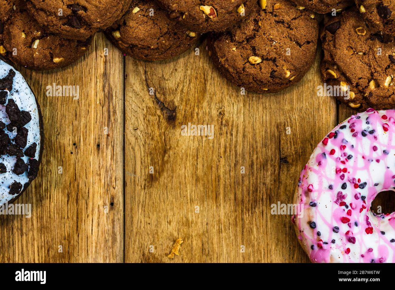 Frame made of chocolate chip cookies, biscuits and colorful donuts top ...