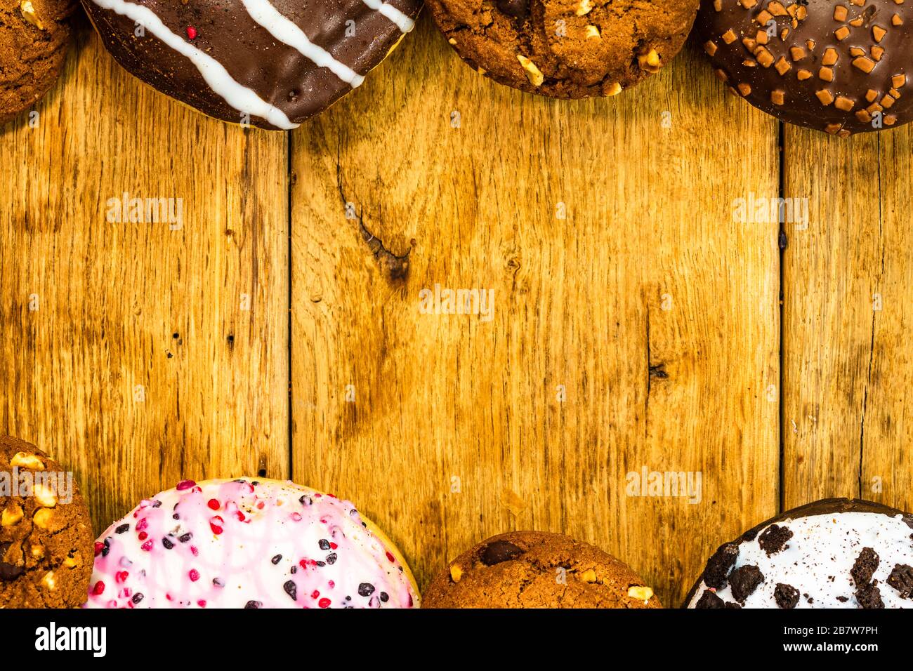 Frame made of chocolate chip cookies, biscuits and colorful donuts top ...