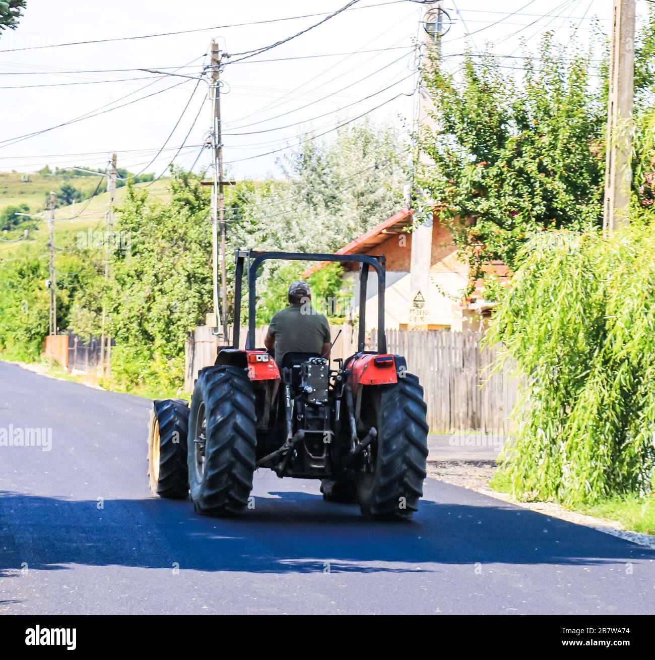 Back view of agricultural tractor moving on the asphalt road after ...