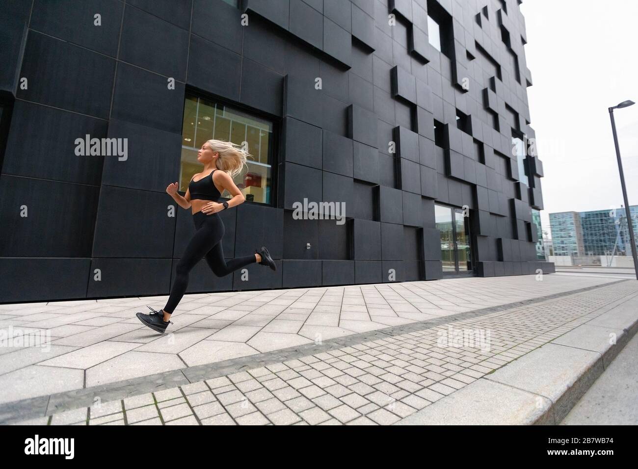 Fast running woman wearing sports top in modern city environment Stock ...