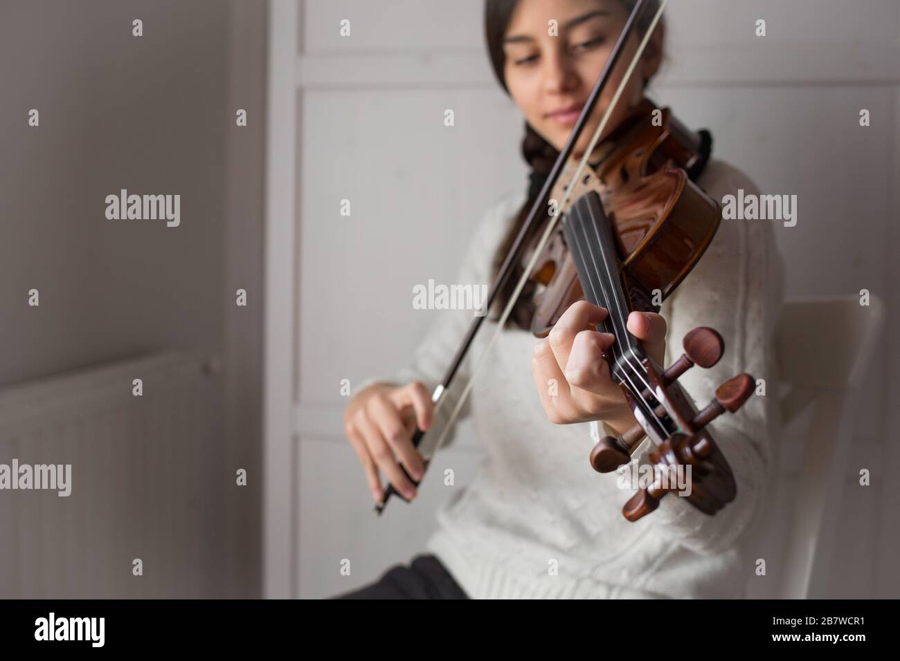 Young student smiling practice violin at home with white background ...