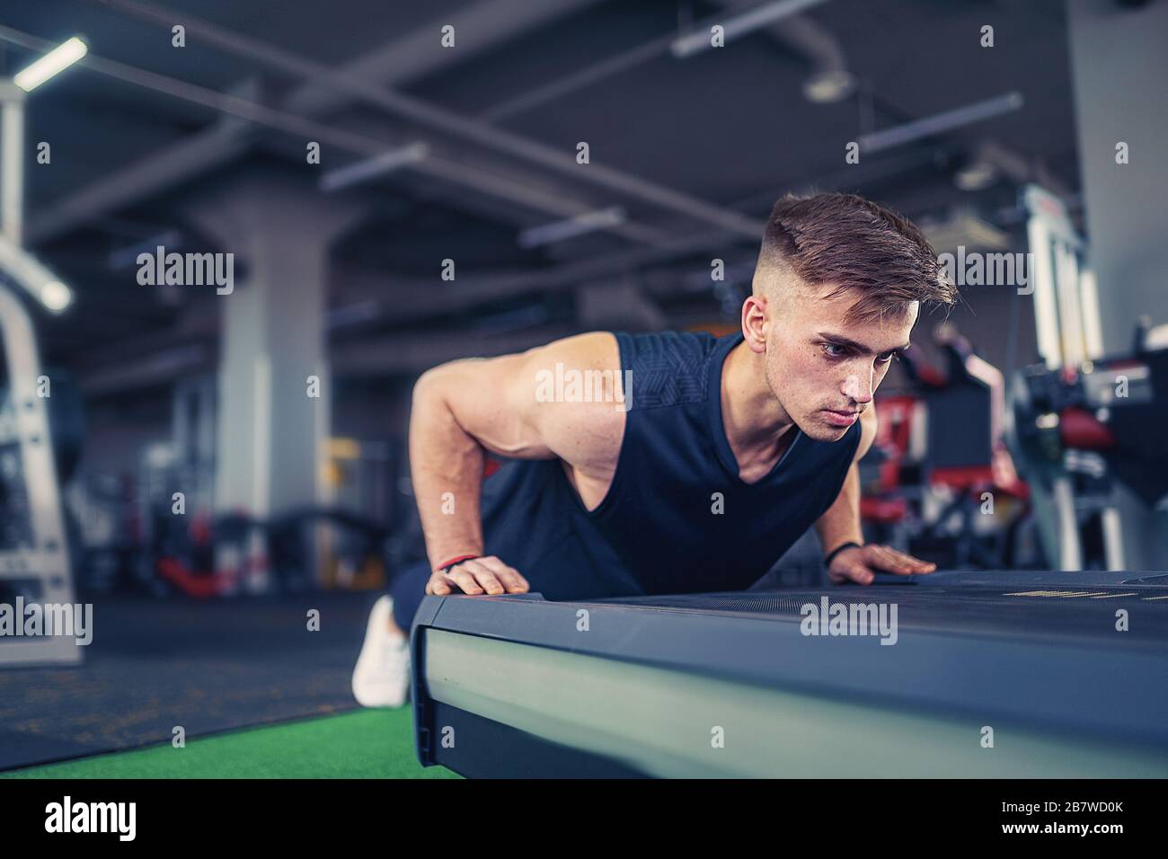 Young athletic man doing push-ups in gym. Muscular and strong guy ...