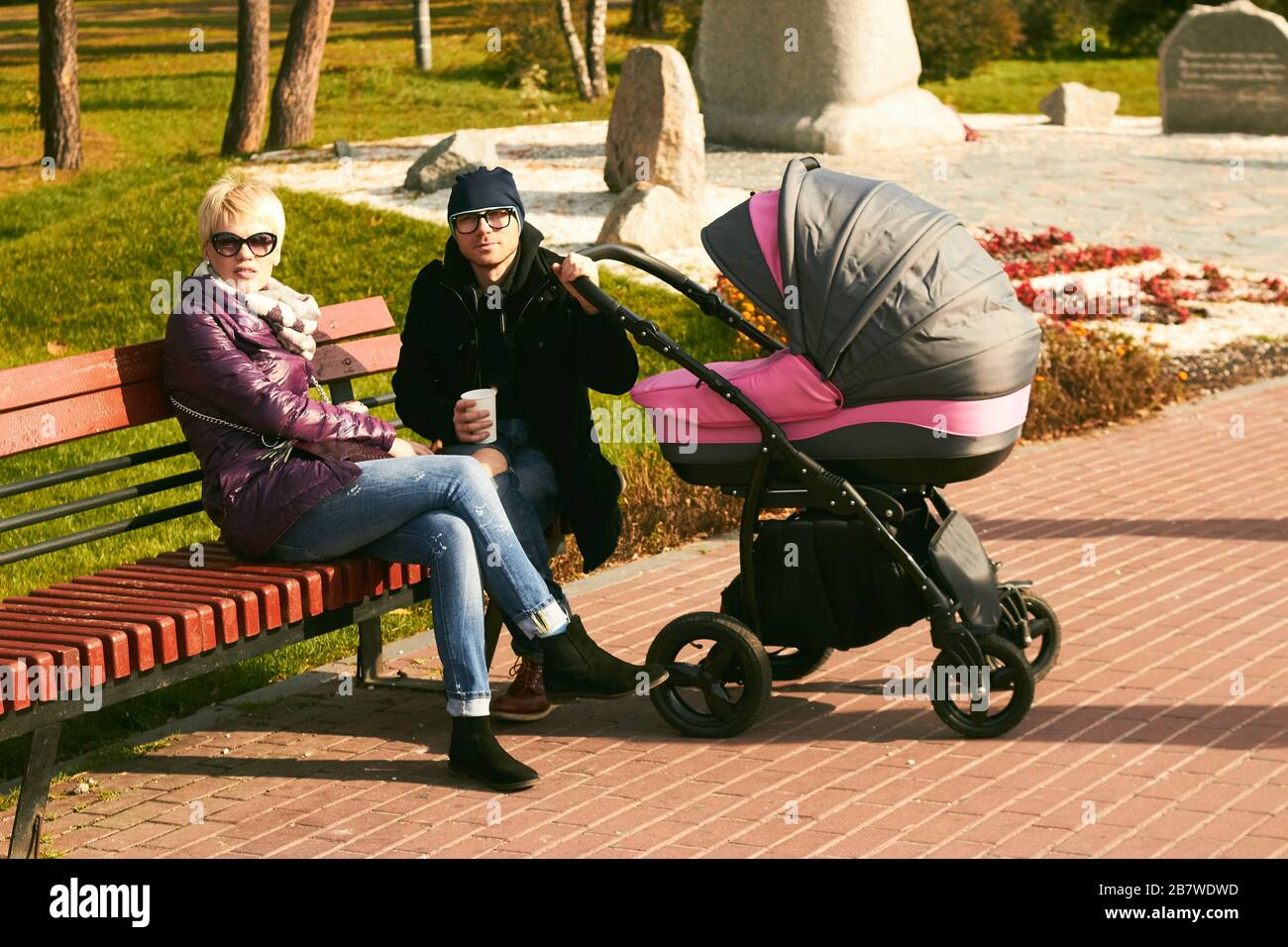 Family walk in the autumn park with a pram. Mom, dad and baby outdoors ...