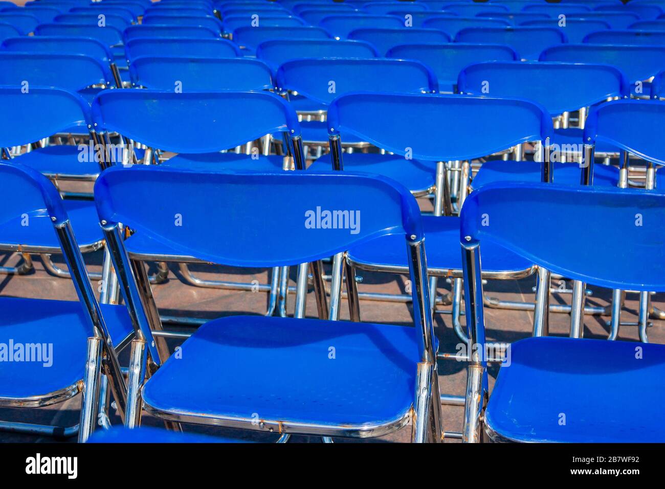 Rows of blue seats in the park with chairs set aside for the concert ...