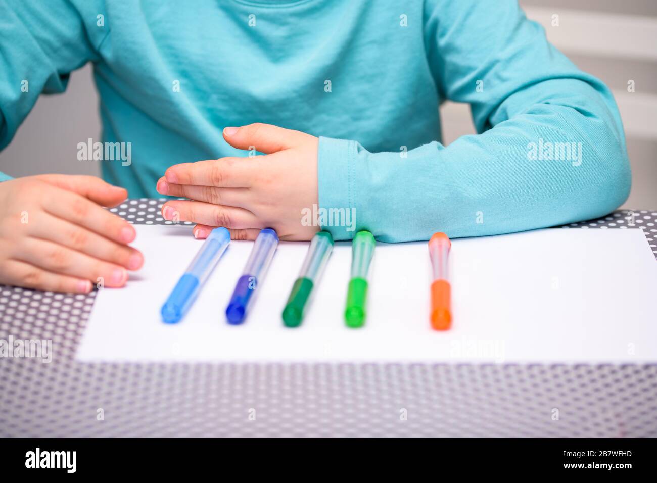 Close-up of five year old boy playing and lining up color pens on a ...
