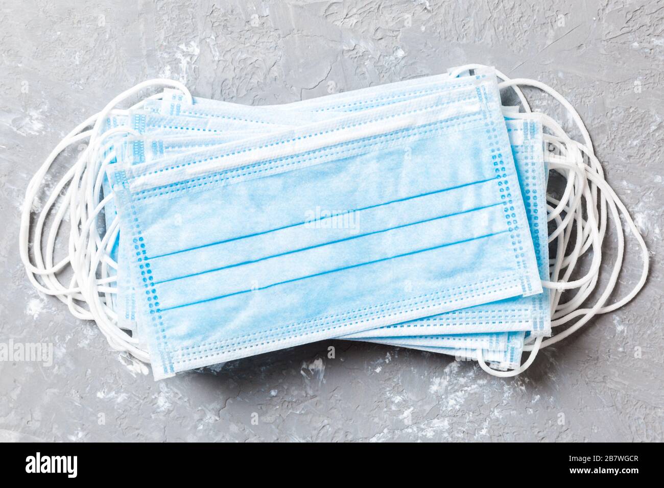 Pile of protective medical masks on cement background. Respiratory ...