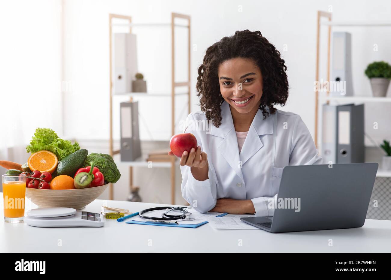 Attractive woman doctor kindly recommending eating fresh fruits Stock ...