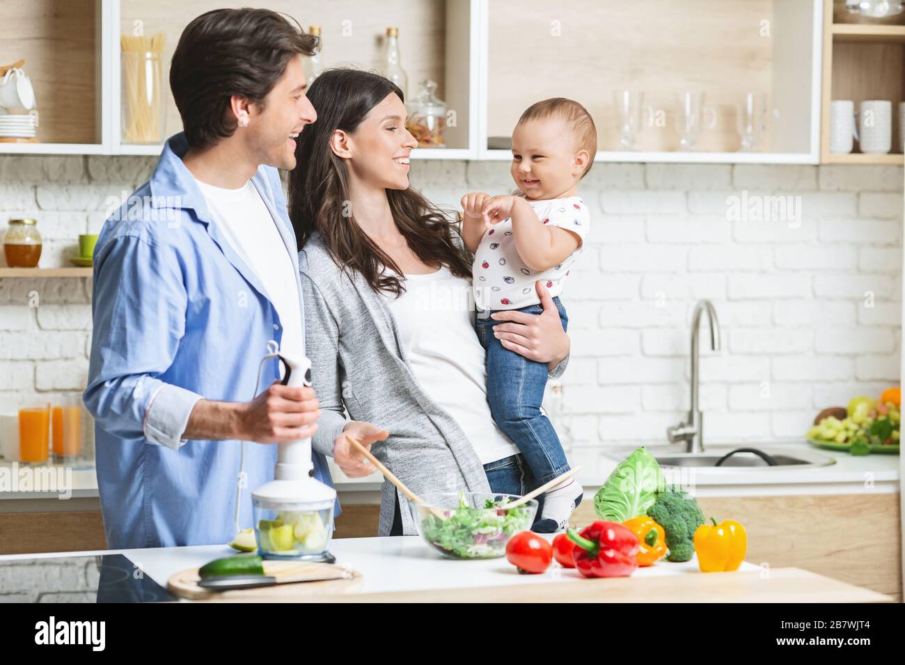 Happy family of three cooking together at kitchen Stock Photo - Alamy