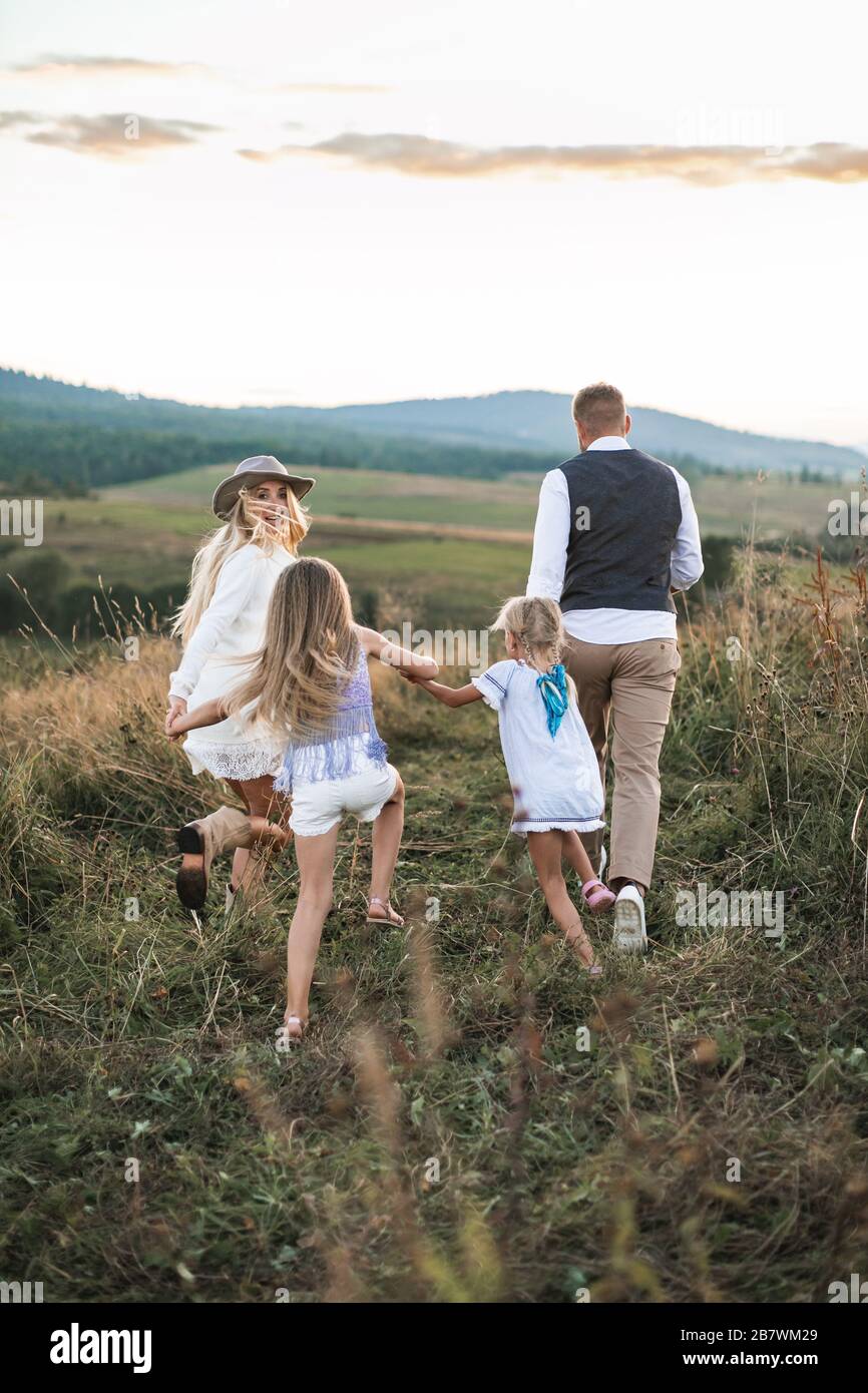 Summertime in the countryside. Back view of the family with two little ...