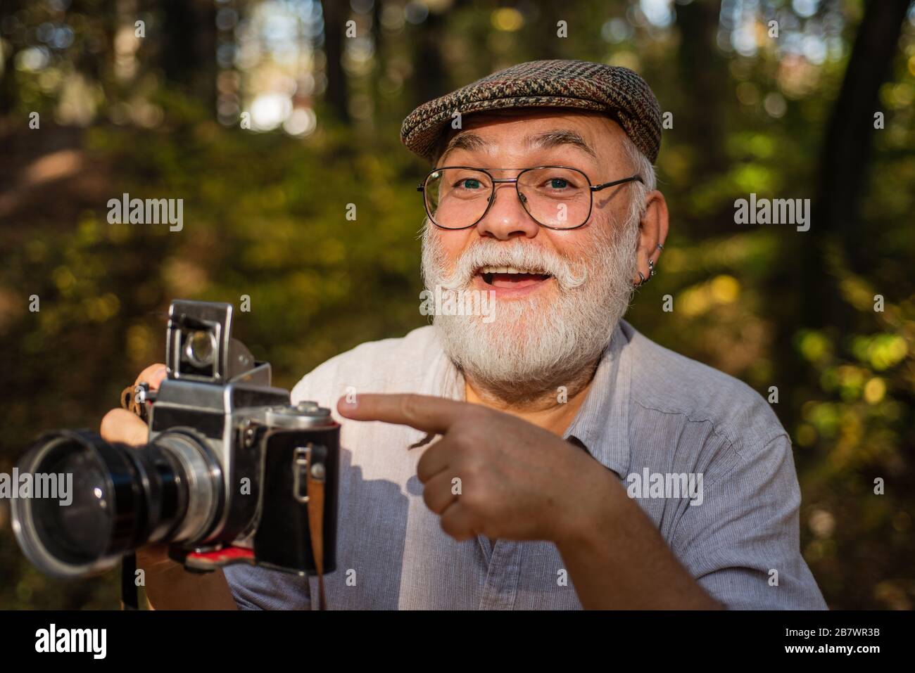Look at this. Old photographer pointing at retro camera. Bearded man ... Look at this. Old photographer pointing at retro camera. Bearded man ...