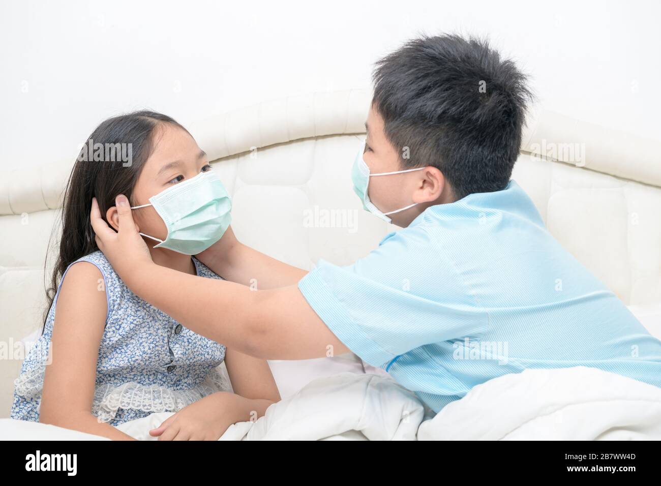 Brother helping his sister wearing surgical mask on bed, Wuhan ...