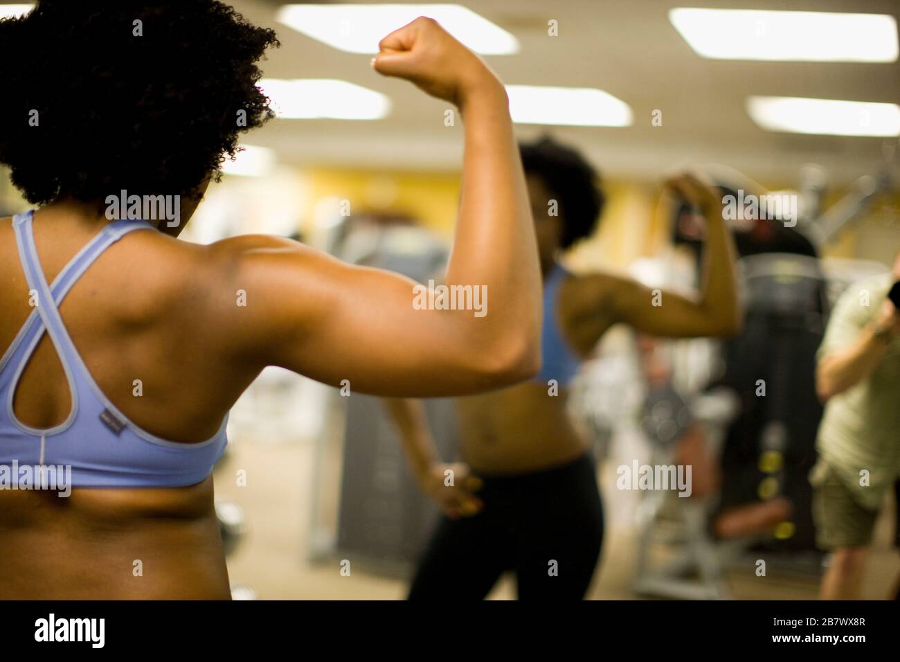 Young woman flexing her muscles at a gym Stock Photo - Alamy