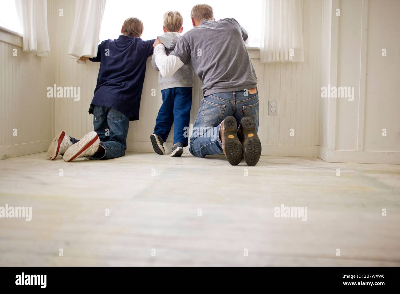 Father and sons looking out the window Stock Photo - Alamy
