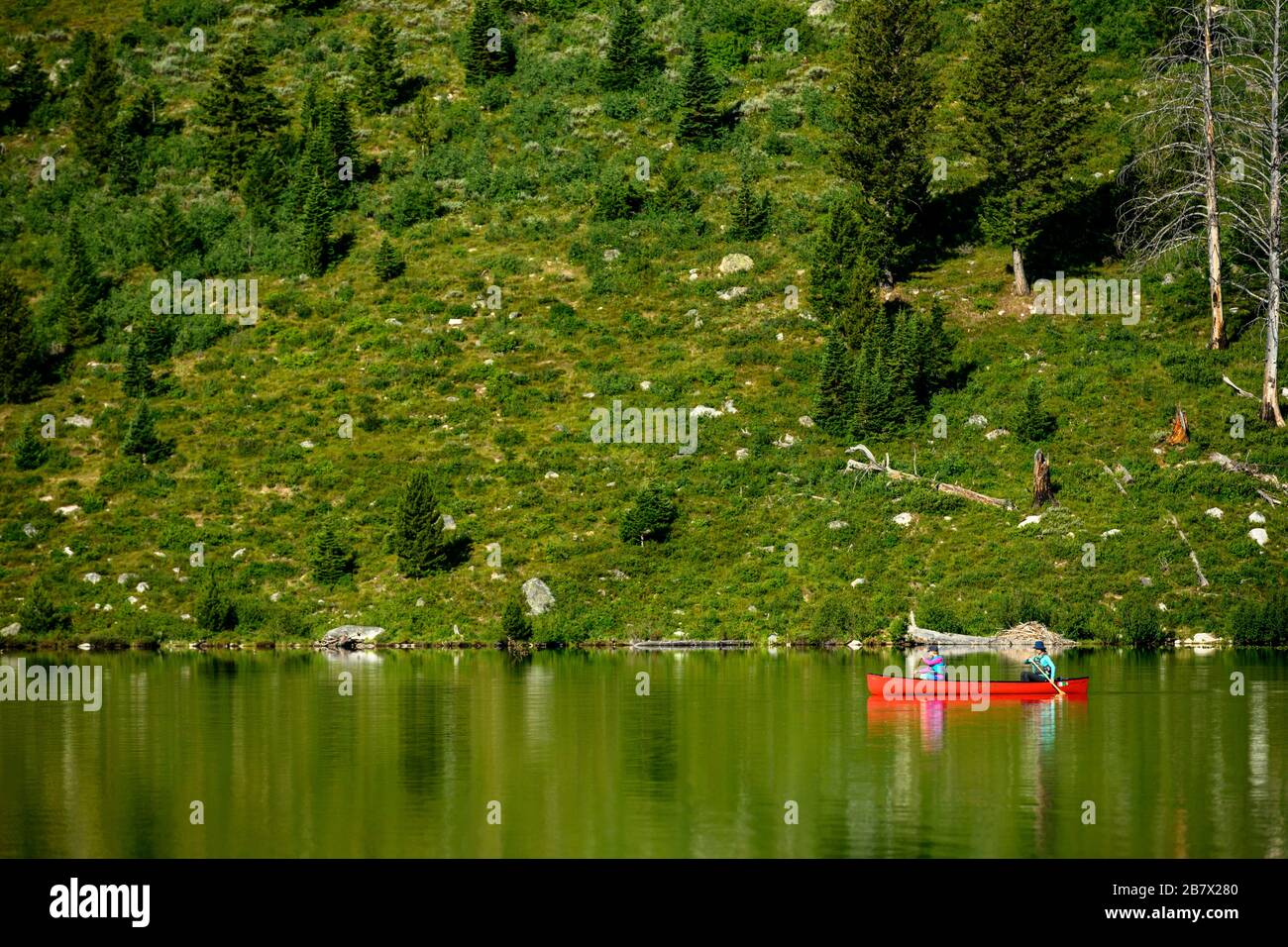 Red Canoe on Lake Reflecting Green Hillside Stock Photo - Alamy