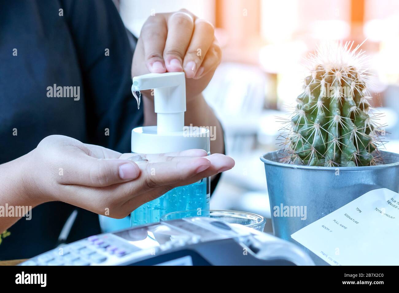 Young woman uses her hand to press hand sanitizer bottle to clean her ...