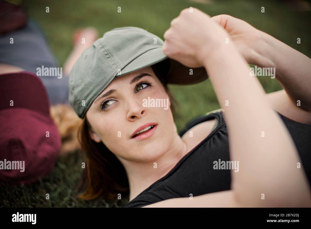 Young woman twisting her cap around while lying down with a friend in ...