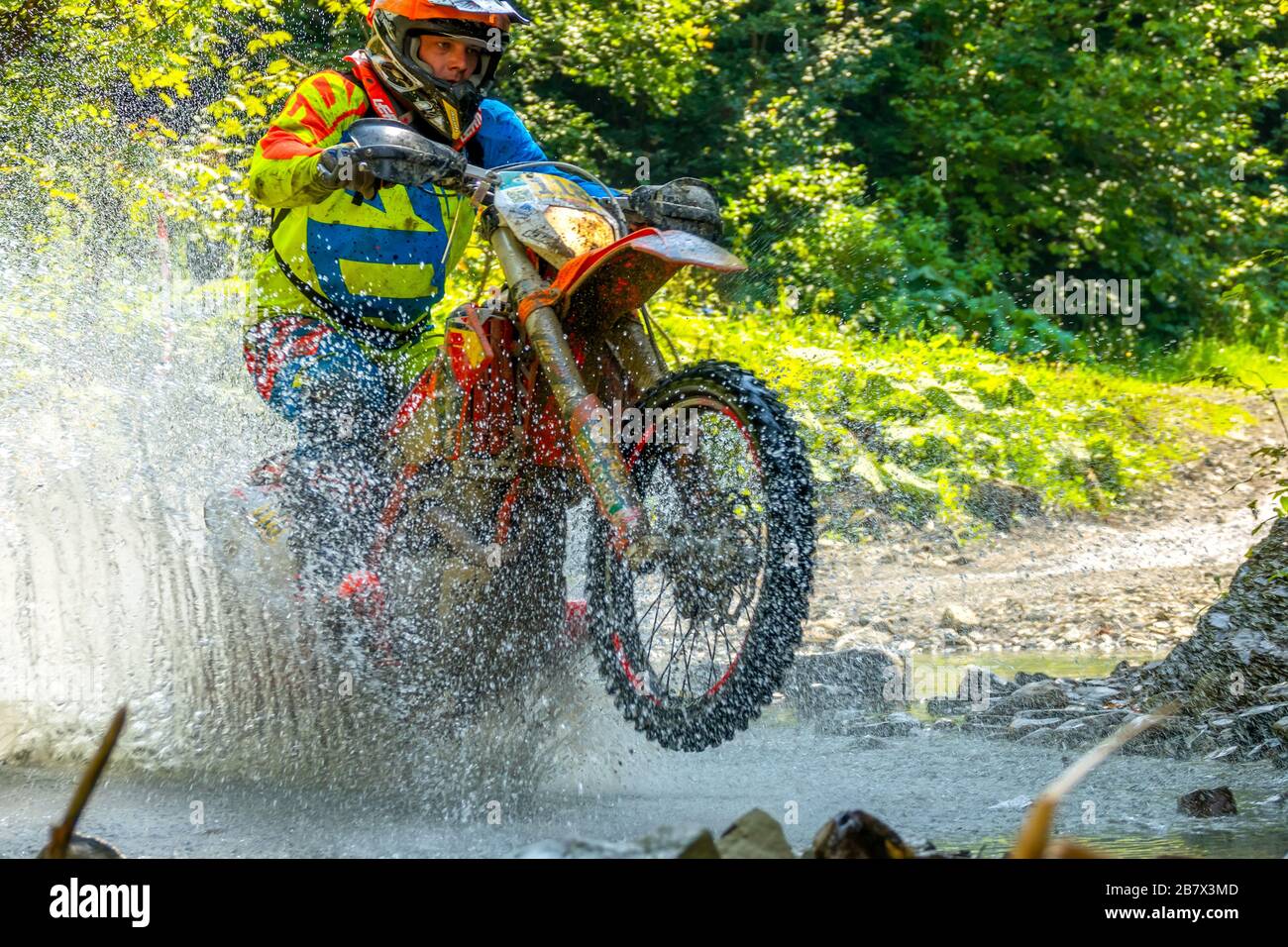 Summer sunny day. A lot of splash of water hides an enduro motorcycle ...