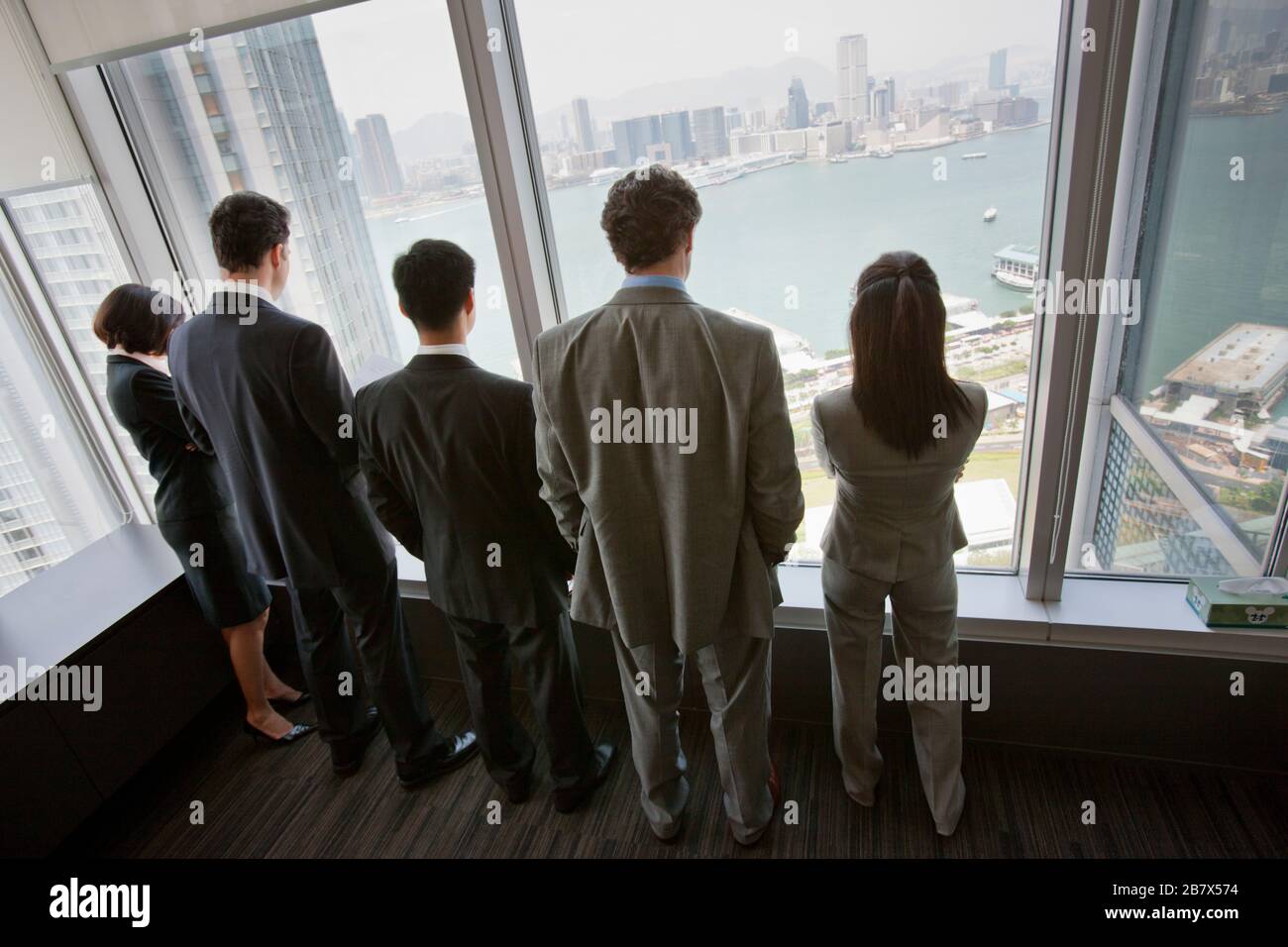 Group of colleagues looking out a window together in their office ...