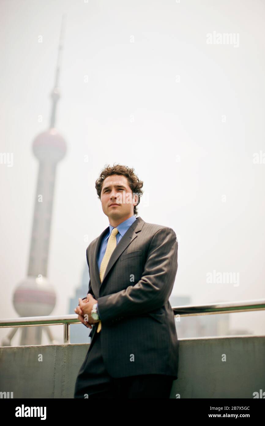Businessman leaning against railing Stock Photo - Alamy