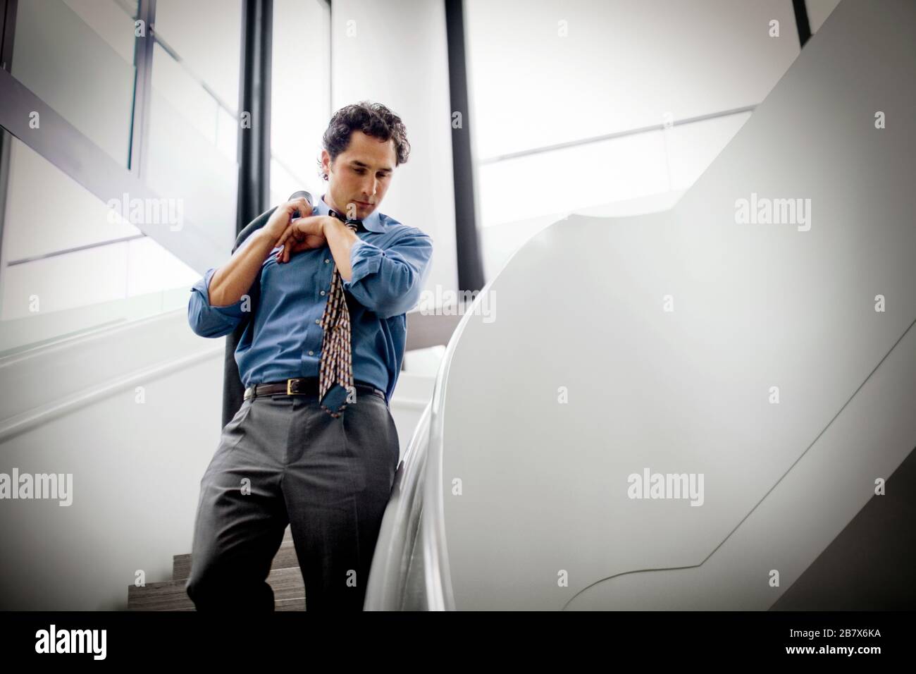 Young businessman walking down a staircase with his suit jacket slung ...