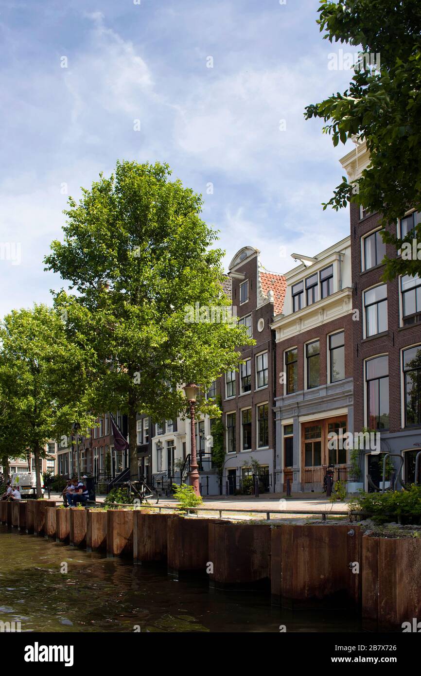View of people hanging out by canal, trees, historical and traditional ...