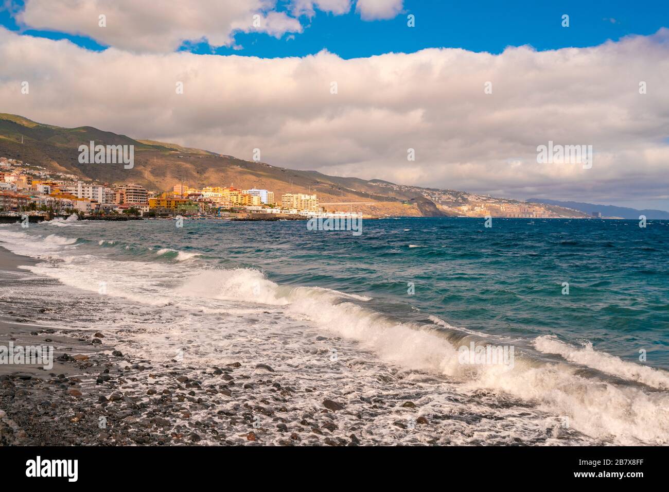 View of the black beach in Candelaria with resorts and mountains Stock ...