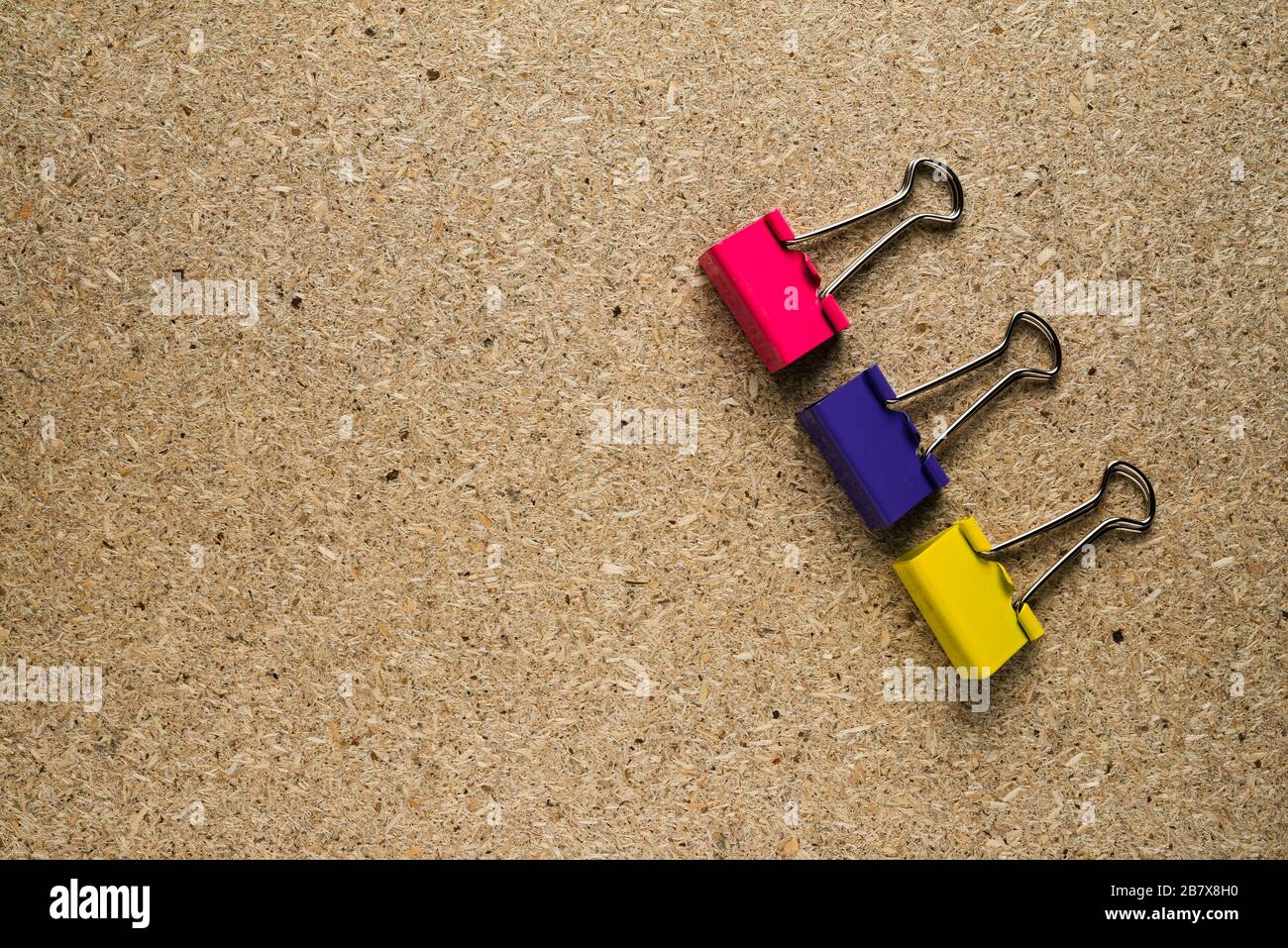 Paper clip. Three colored clothespins on a chipboard Stock Photo - Alamy