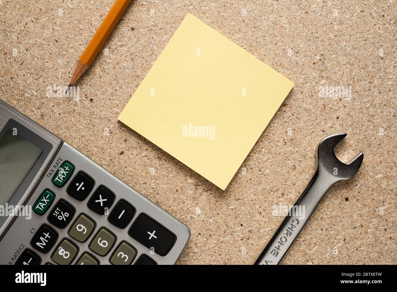 Calculator, pencil, wrench and notepad on a chipboard table Stock Photo ...