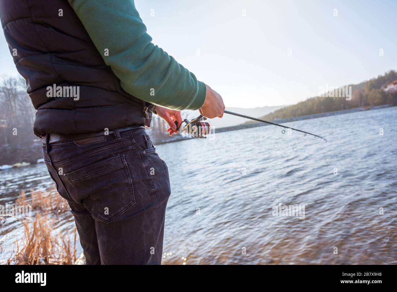Angler catching fish in the lake during cloudy sunrise Stock Photo - Alamy
