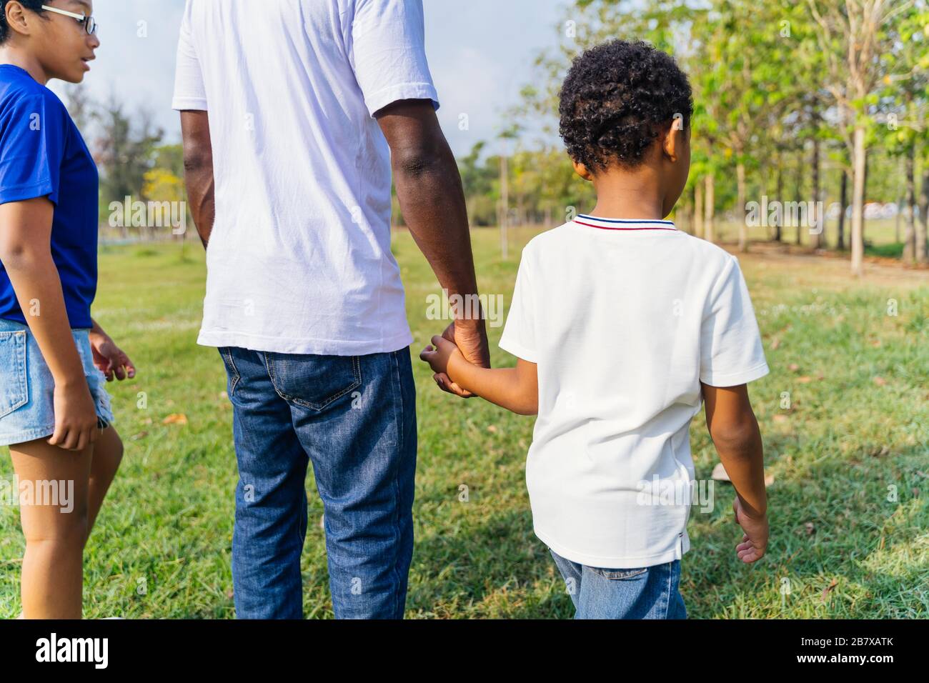African American father walking in the countrside nature with pre-teen ...