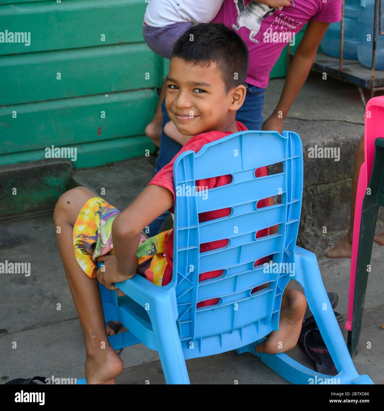 Happy boy sitting in a blue chair, Los Fuertes, Roatan, Honduras Stock ...