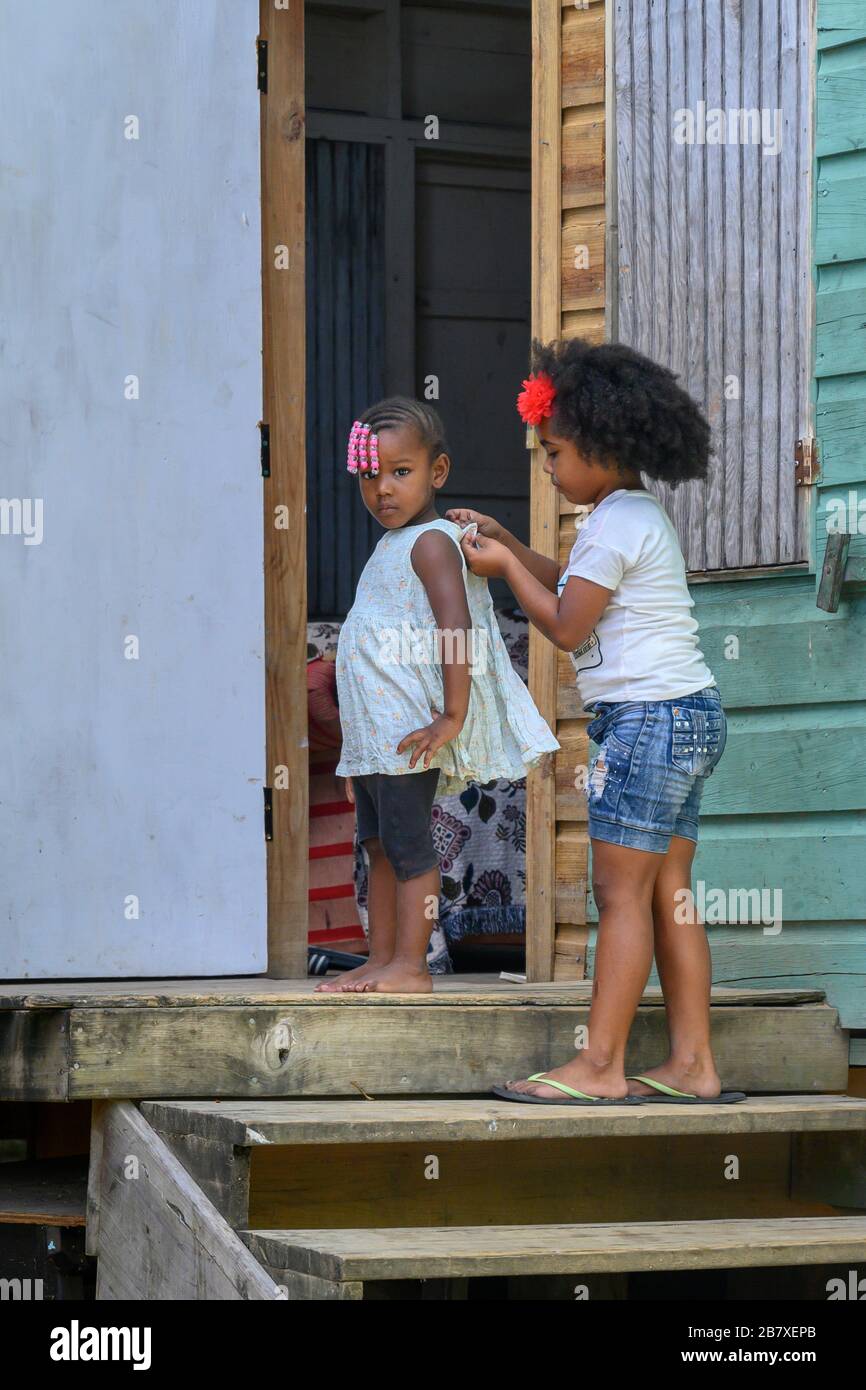 Girl helping her younger sister to get dressed, Los Fuertes, Roatan ...