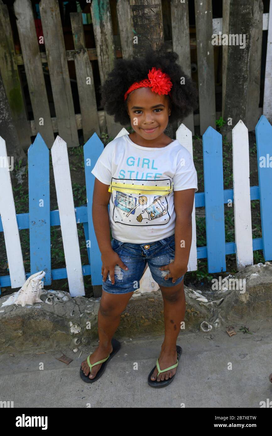 Young girl standing in front of picket fence, Los Fuertes, Roatan ...