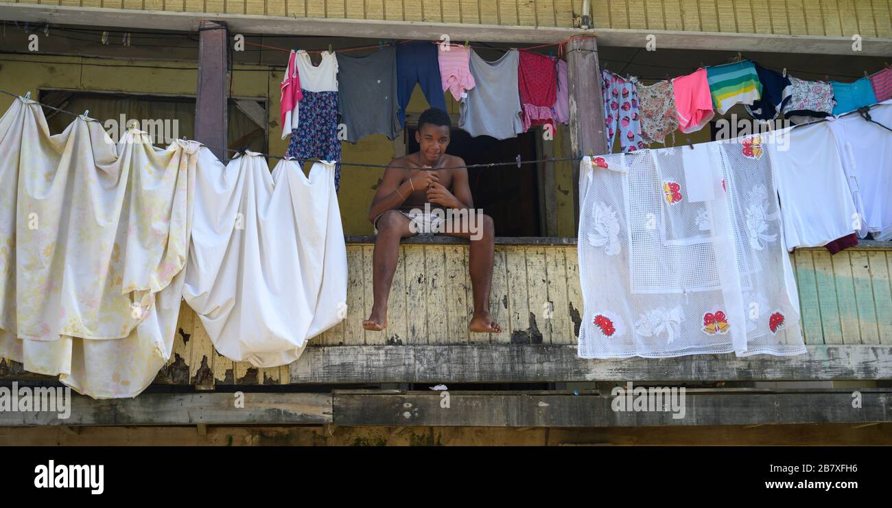 Teenage boy sitting on railing of balcony, Los Fuertes, Roatan ...